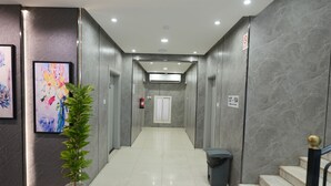 Um corredor moderno com planta em vaso, escada e extintor de incêndio.