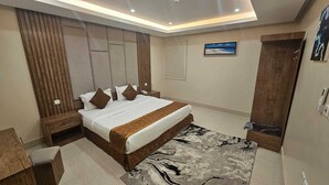 Quarto moderno com uma cama grande, cabeceira de madeira, mesas de cabeceira, um criado-mudo, guarda-roupa e um tapete estampado.