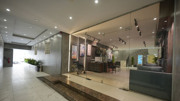 Um hall de hotel moderno com balcão de recepção, área de estar e escadaria para os andares superiores.