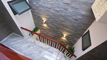 Um interior moderno com escadaria de mármore, parede texturizada e uma pequena planta em vaso.