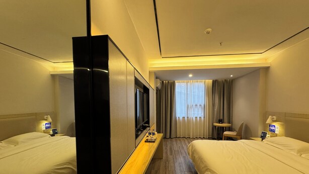 Quarto de hotel com duas camas, televisão, escrivaninha e uma pequena mesa.
