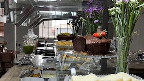 Buffet com diversos alimentos, incluindo bolos e vários pratos em recipientes.