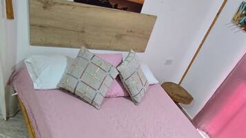 Quarto com cama, cabeceira, quadro, mesa de cabeceira e tapete.
