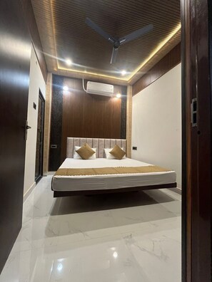 Quarto moderno com cama, ventoinha no teto e aparelho de ar condicionado.