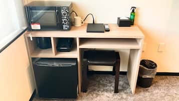 Uma cozinha compacta equipada com micro-ondas, cafeteira e lixeira.