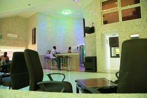 Um saguão de hotel com balcão de recepção, área de estar e parede estampada.