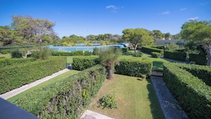Um jardim bem cuidado com sebes aparadas, um caminho bem definido e vista para um edifício ao longe.