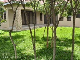Um edifício com fachada bege, um pilar de pedra e telhado de telhas.
