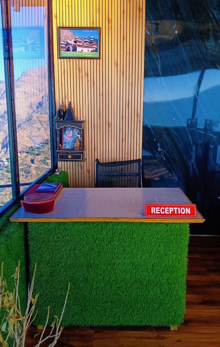 Balcão de recepção com placa 'RECEPTION', um quadro na parede e uma cadeira.