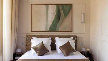 Uma cama bem arrumada com cabeceira estampada, uma grande pintura abstrata acima e uma mesa de cabeceira com abajur à direita.