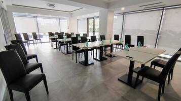 Sala de conferência com várias mesas e cadeiras, amplas janelas e design moderno.