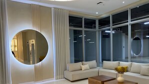 Uma sala de estar moderna com um sofá seccional, duas mesas de centro de madeira e um espelho grande.