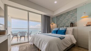 Quarto de hotel moderno com uma cama grande, varanda com vista, escrivaninha e uma cadeira.