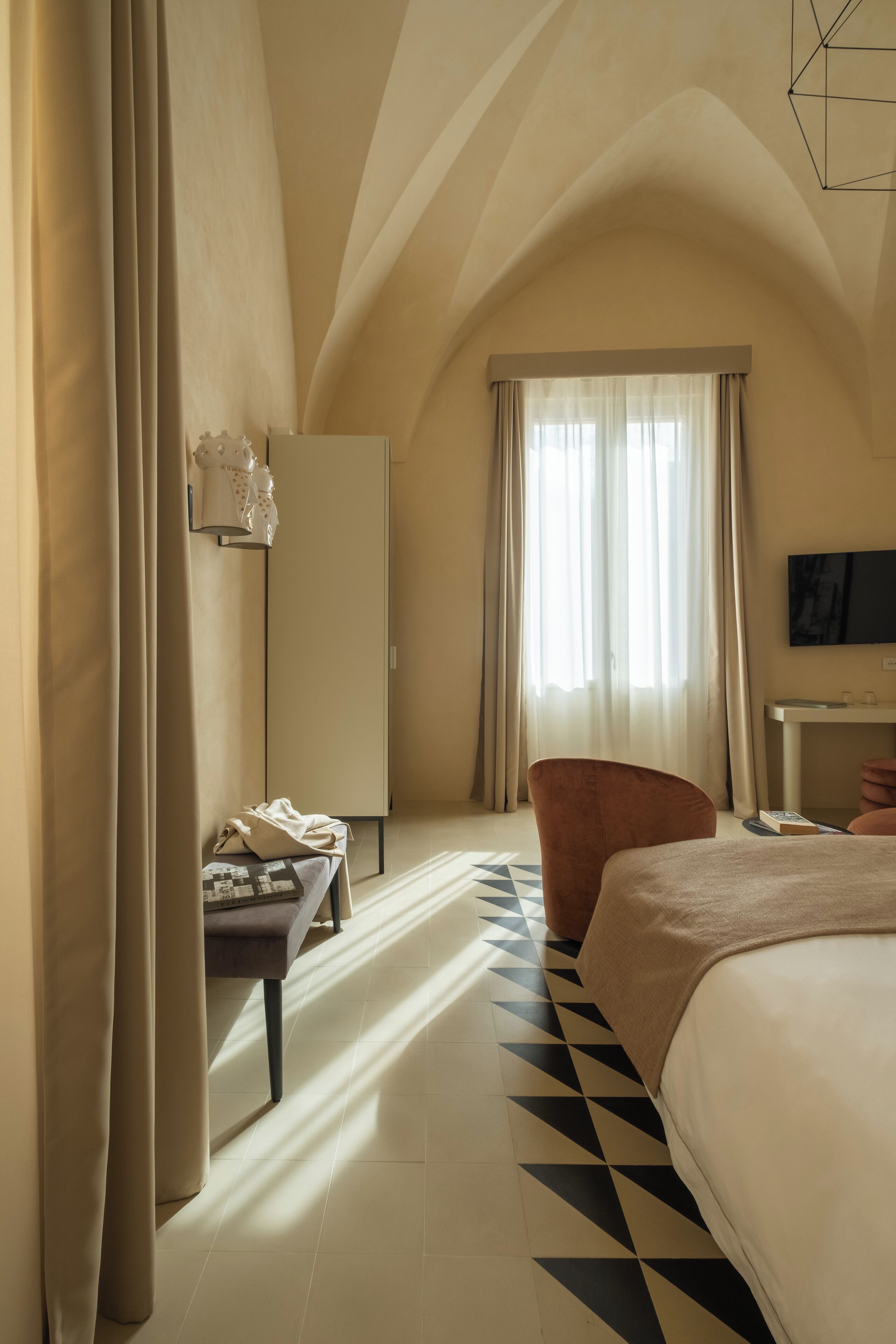 Quarto de hotel com cama, escrivaninha, cadeira e guarda-roupa.