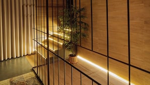 Um interior moderno com divisória de madeira, iluminação embutida e um vaso de planta.