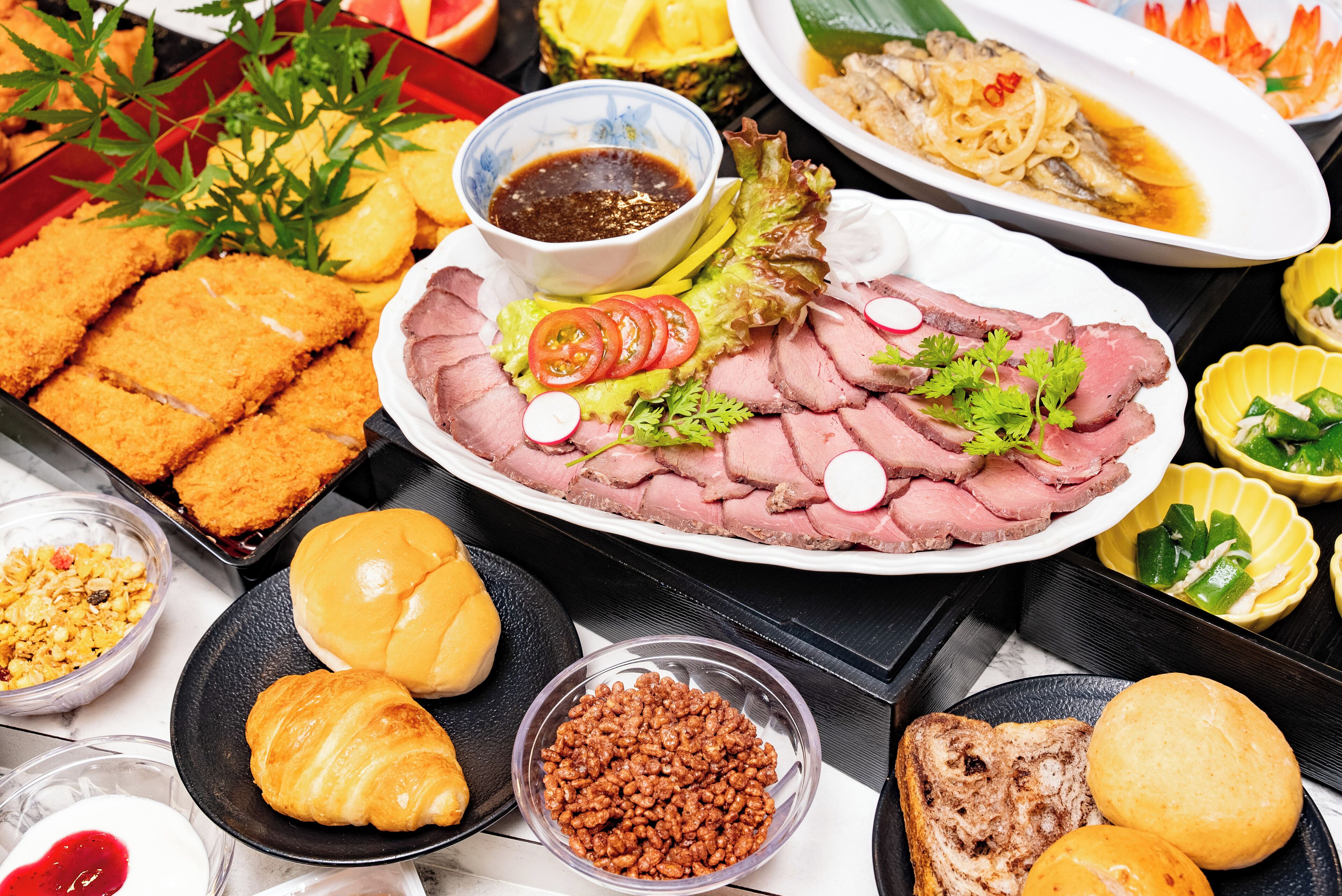 Diversos alimentos como pão, croissants e um prato com carne fatiada, sugerindo um buffet ou refeição.