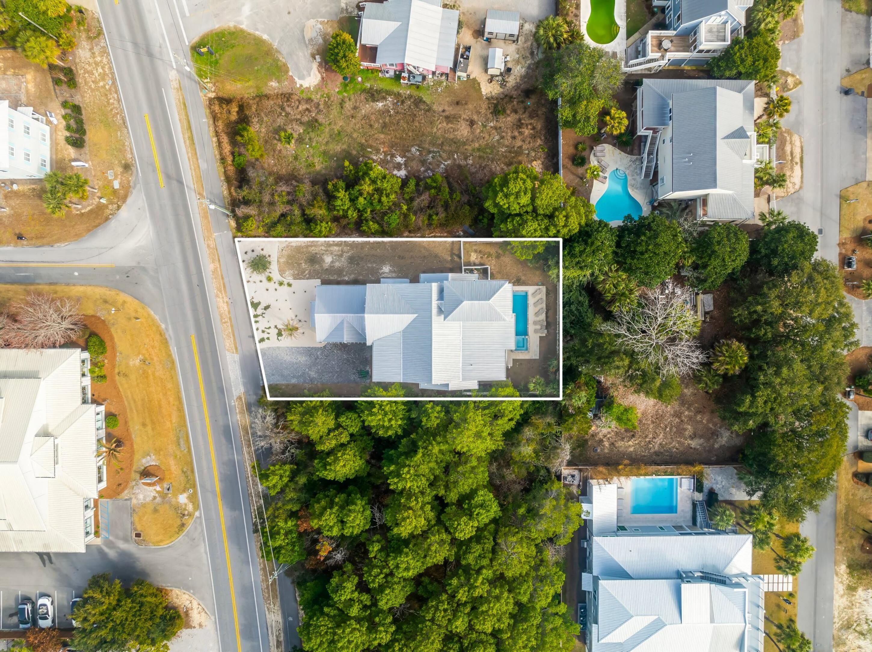 Vista aérea de um bairro residencial, com casas, uma rua e uma grande área verde com árvores.