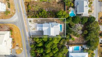 Vista aérea de um bairro residencial, com casas, uma rua e uma grande área verde com árvores.