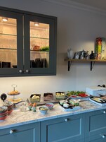 Cozinha com bancada de mármore, armários de vidro e diversos alimentos.