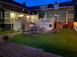 Uma casa de dois andares com varanda coberta, uma pequena escadaria e um jardim.