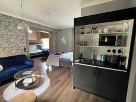 Quarto de hotel compacto com cozinha compacta, sofá, mesa de centro e cama.