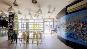 Um quarto espaçoso com uma grande janela, ar-condicionado na parede e uma mesa com cadeiras.