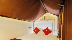 Cama com colchão branco e almofadas vermelhas, sob um dossel marrom.