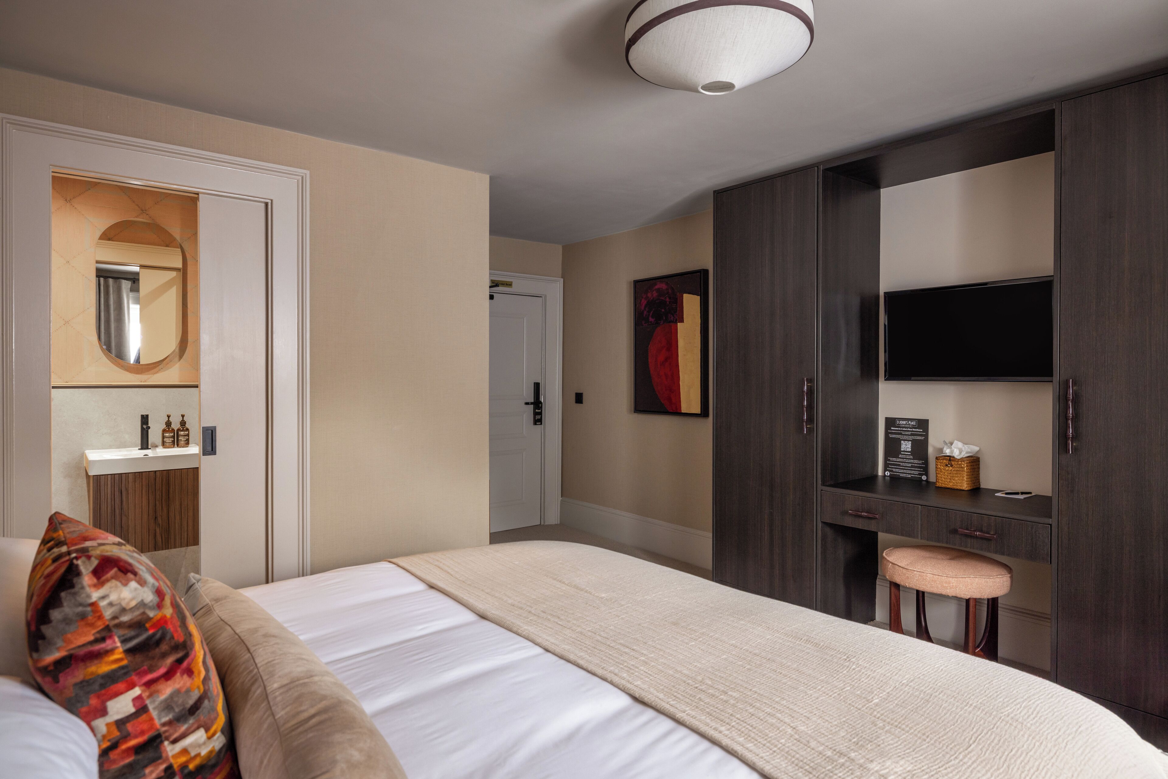 Quarto de hotel com uma cama grande, um espelho, uma televisão e um guarda-roupa.