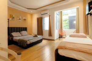Quarto com duas camas, janela com cortinas, uma cadeira e uma obra de arte na parede.