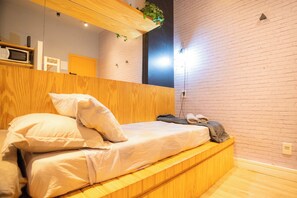 Quarto moderno com cama de madeira, uma prateleira pequena e parede com lousa.