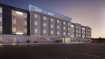 Um hotel moderno com uma placa que diz "EVERHOME SUITES" e um mural dando as boas-vindas aos visitantes em Yuma, Arizona.