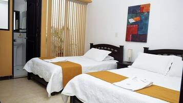 Quarto de hotel com duas camas, banheiro e um quadro na parede.