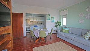 Espaço compacto com área de refeições, bancada de cozinha e sofá.