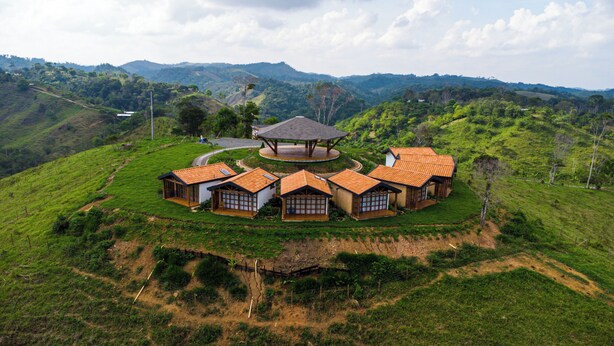 Um conjunto de edifícios em estilo tradicional com um pavilhão central, rodeado por colinas verdejantes.