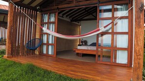 Um deck de madeira com uma rede, uma cadeira azul e uma cama com vista para o exterior.
