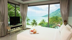 Quarto de hotel com uma cama grande, uma TV em suporte e uma bandeja de café da manhã sobre a cama.