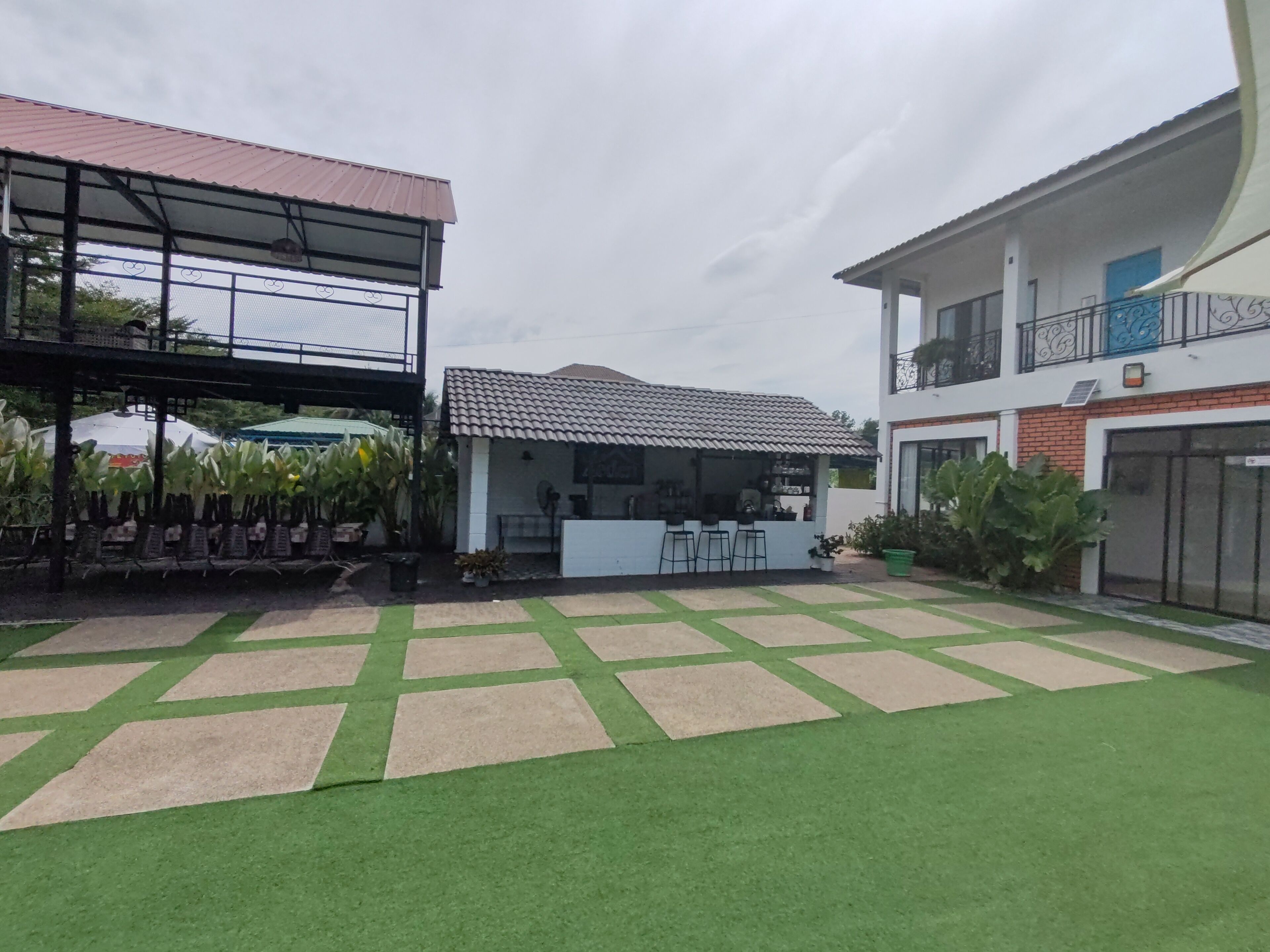 Um pátio com grama sintética e um espaço de bar com banquetas.