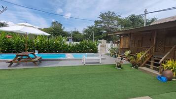 Um quintal com piscina, um banco de madeira e uma pequena área de jardim.