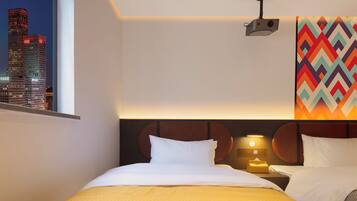 Quarto de hotel com uma cama, mesa de cabeceira, abajur e vista para a cidade.