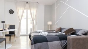 Quarto de hotel moderno com uma cama, uma escrivaninha, uma cadeira e um abajur.
