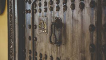 Uma porta de madeira com rebites metálicos e uma maçaneta decorativa de metal.