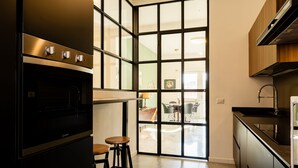 Uma cozinha moderna com forno embutido, coifa de aço inoxidável e uma grande janela com vista para a área de estar externa.