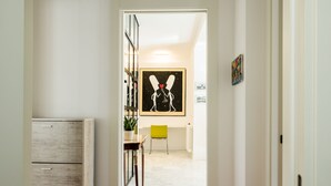 Um corredor com um armário de madeira, uma cadeira e uma obra de arte emoldurada na parede.