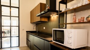 Uma cozinha moderna com armários pretos, um micro-ondas branco e bancada de madeira.