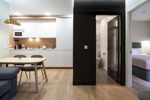 Uma cozinha moderna com armários brancos, micro-ondas e um espaço de refeições com mesa e cadeiras.
