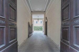 Um corredor com portas de madeira escura, paredes claras e chão de azulejos.