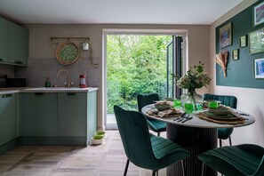 Cozinha moderna com ilha central, cadeiras verdes e mesa de jantar posta para quatro.