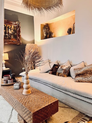 Uma sala de estar moderna com um sofá, almofadas decorativas, uma mesa de centro de fibra natural e obras de arte nas paredes.