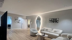 Uma sala de estar moderna com piso de madeira, um sofá, uma mesa de centro e uma TV de tela plana.