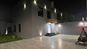 Um edifício moderno com telhado plano, grandes janelas e área de entrada bem iluminada.